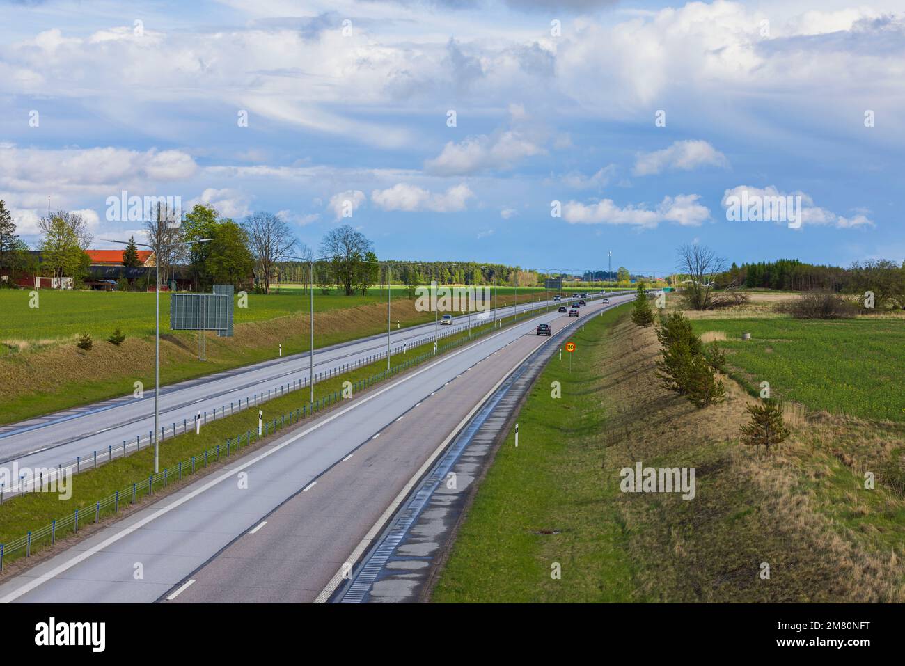 View from bridge to motorway running along fields against blue sky with ...