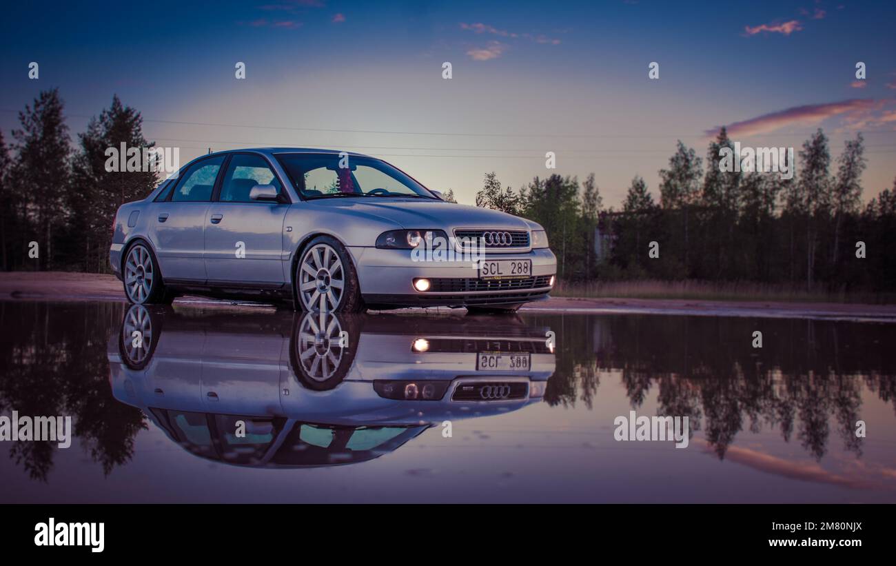 An Audi A4 B5 and its reflection on a wet road at sunset as seen from ...