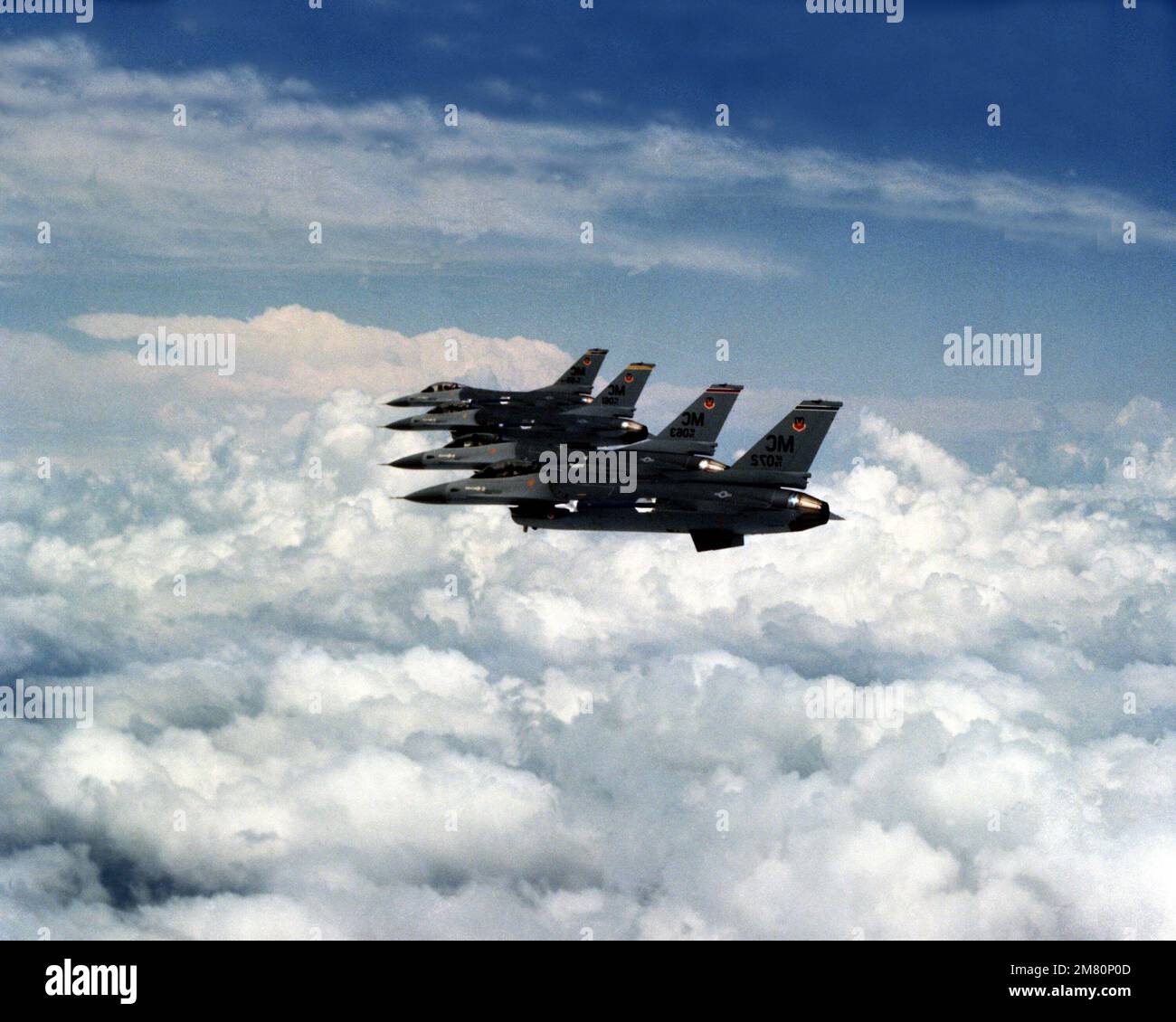 An air-to-air right side view of four F-16A Fighting Falcon aircraft in ...