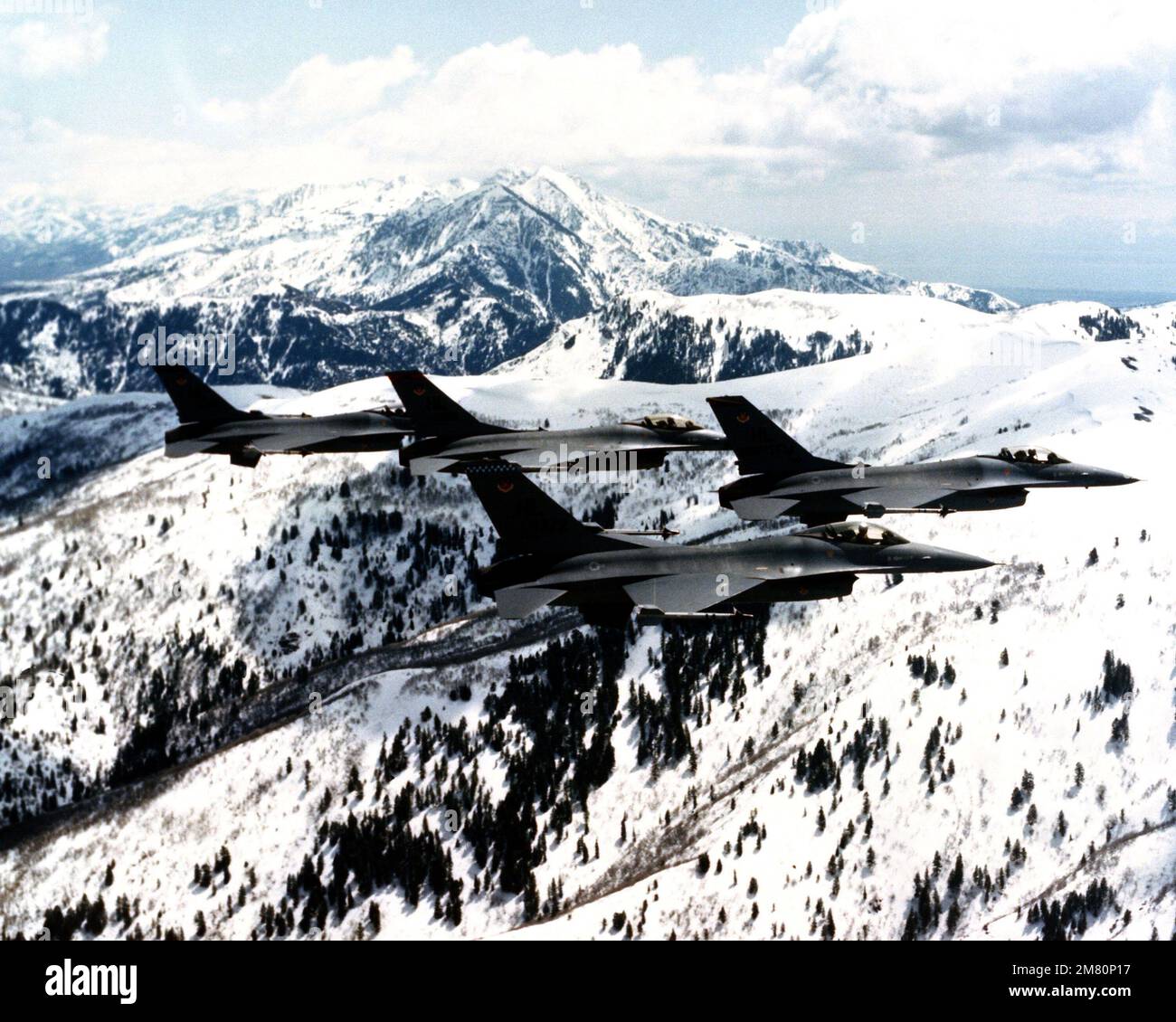 An air-to-air right side view of four F-16 Fighting Falcon aircraft in ...