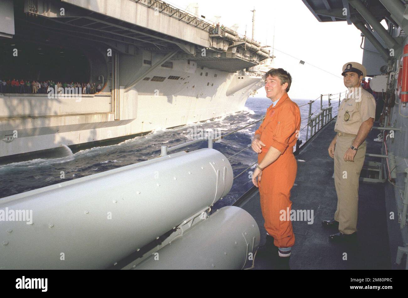 Secretray of the Navy John F. Lehman Jr. looks across from the deck of ...