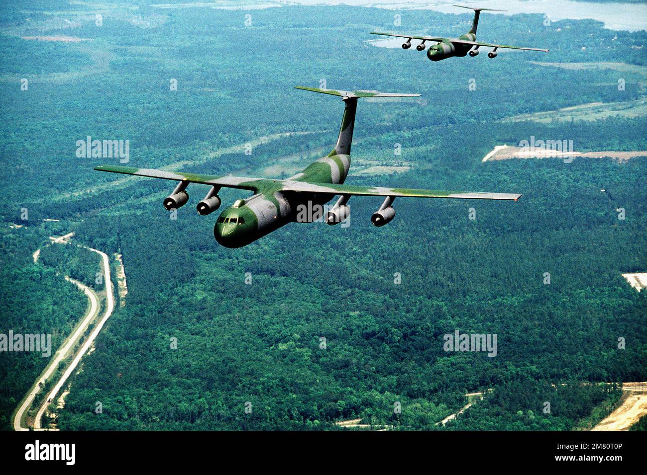 An air-to-air left front view of two C-141 Starlifter aircraft in ...