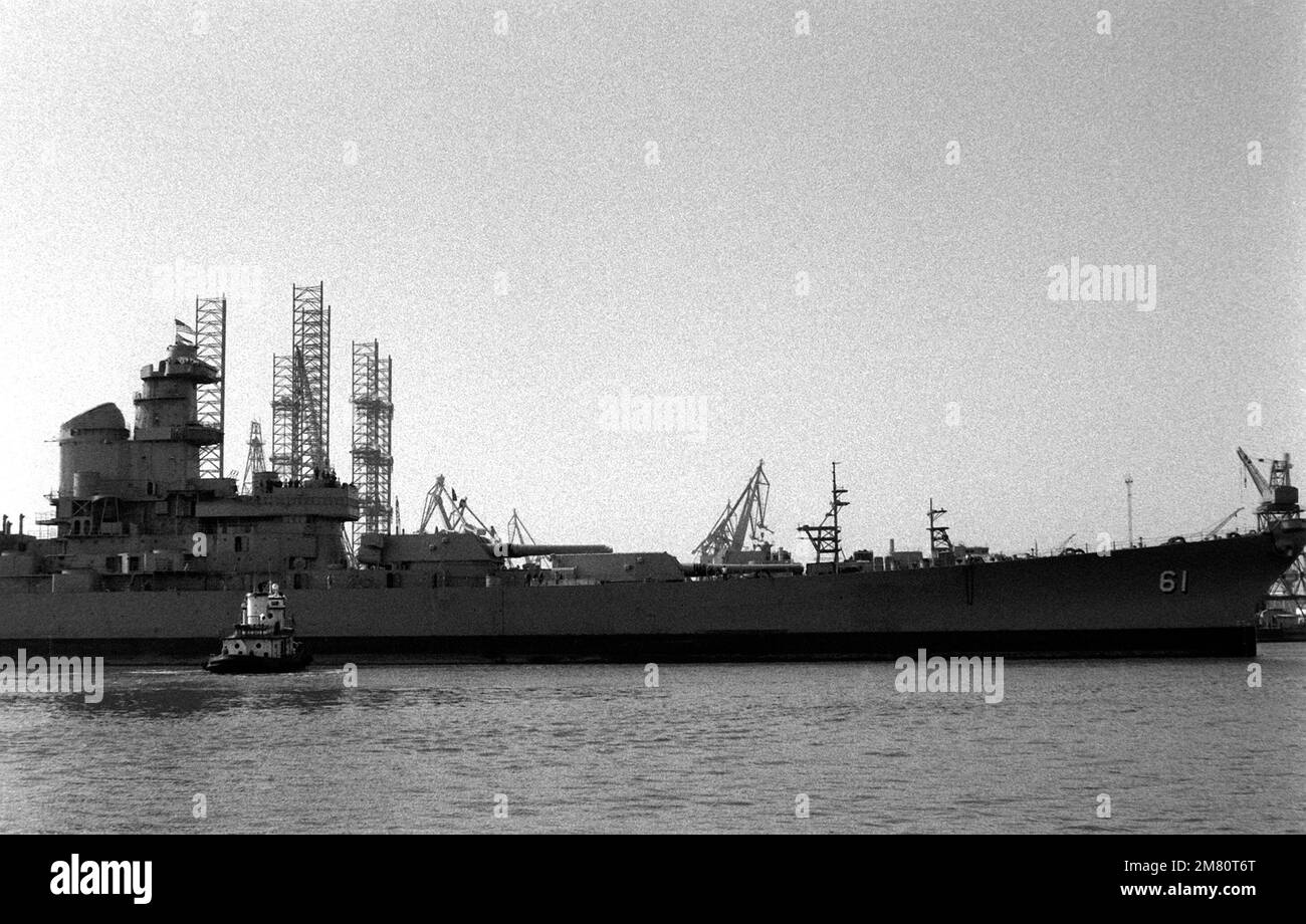 A tugboat assists the battleship USS IOWA (BB-61) into the Ingalls ...