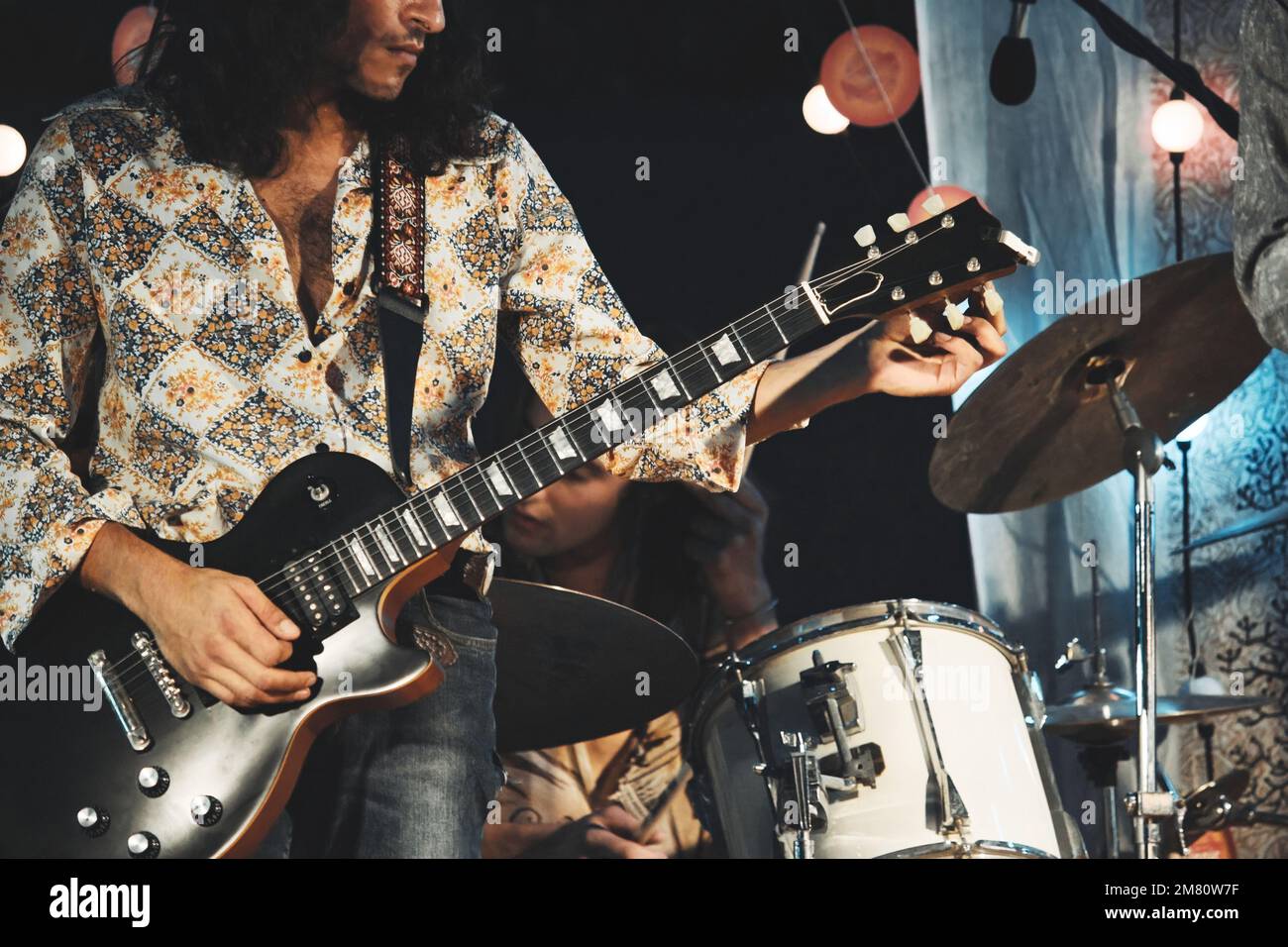 An unrecognisable young man with long hair playing the electric guitar ...