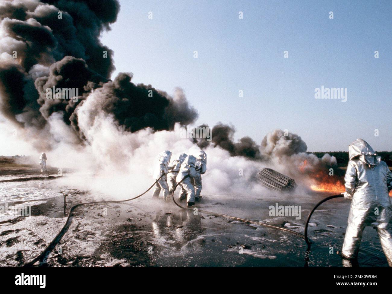 Firemen wearing protective suits extinguish a blaze in a fire pit ...