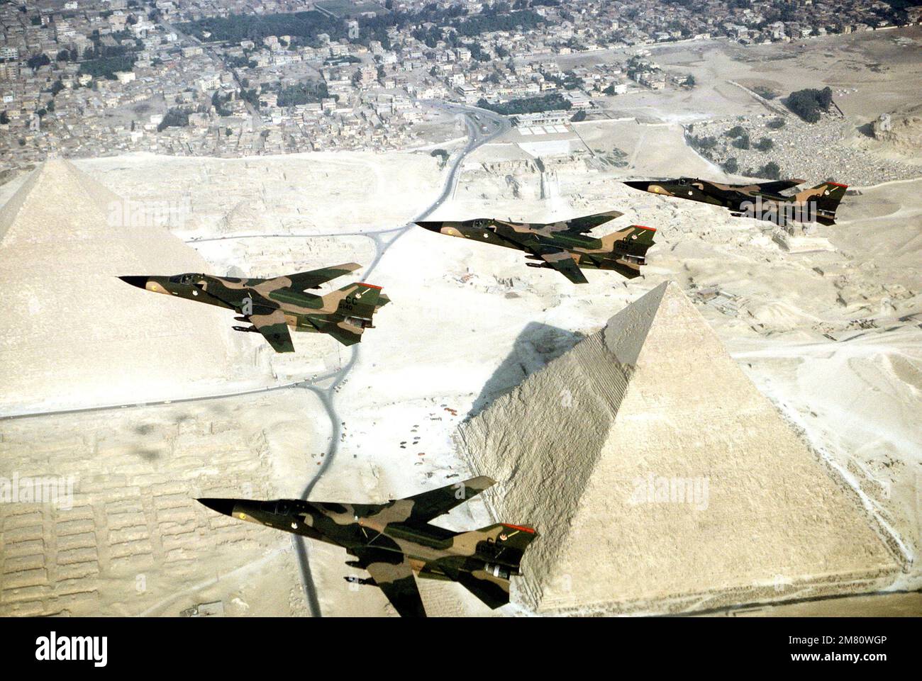 An air-to-air left side view of four F-111 aircraft as they fly over ...