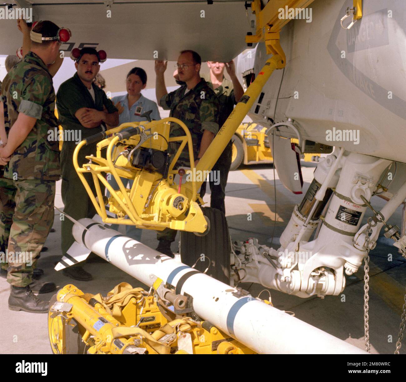 Marine ordnancemen discuss procedures for mounting an NAIM-120A ...