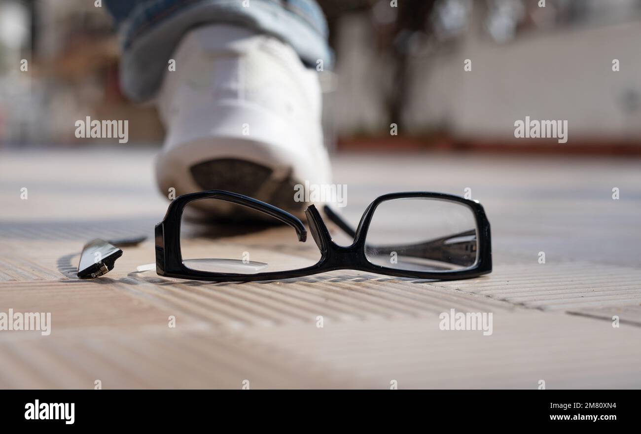foot stepped on glasses. accident on st. broken glasses on street tiles ...