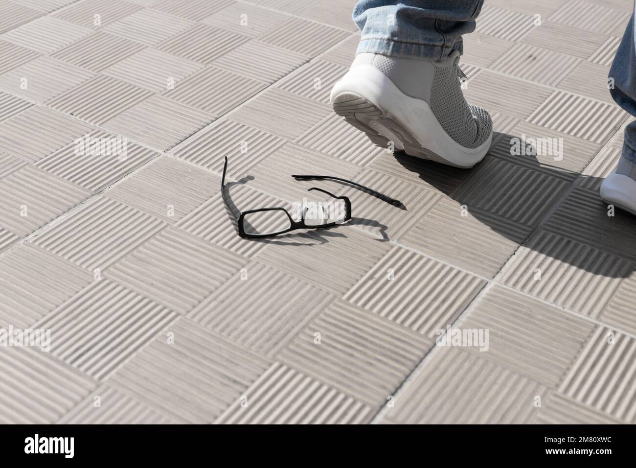 foot stepped on glasses. accident on st. broken glasses on street tiles ...