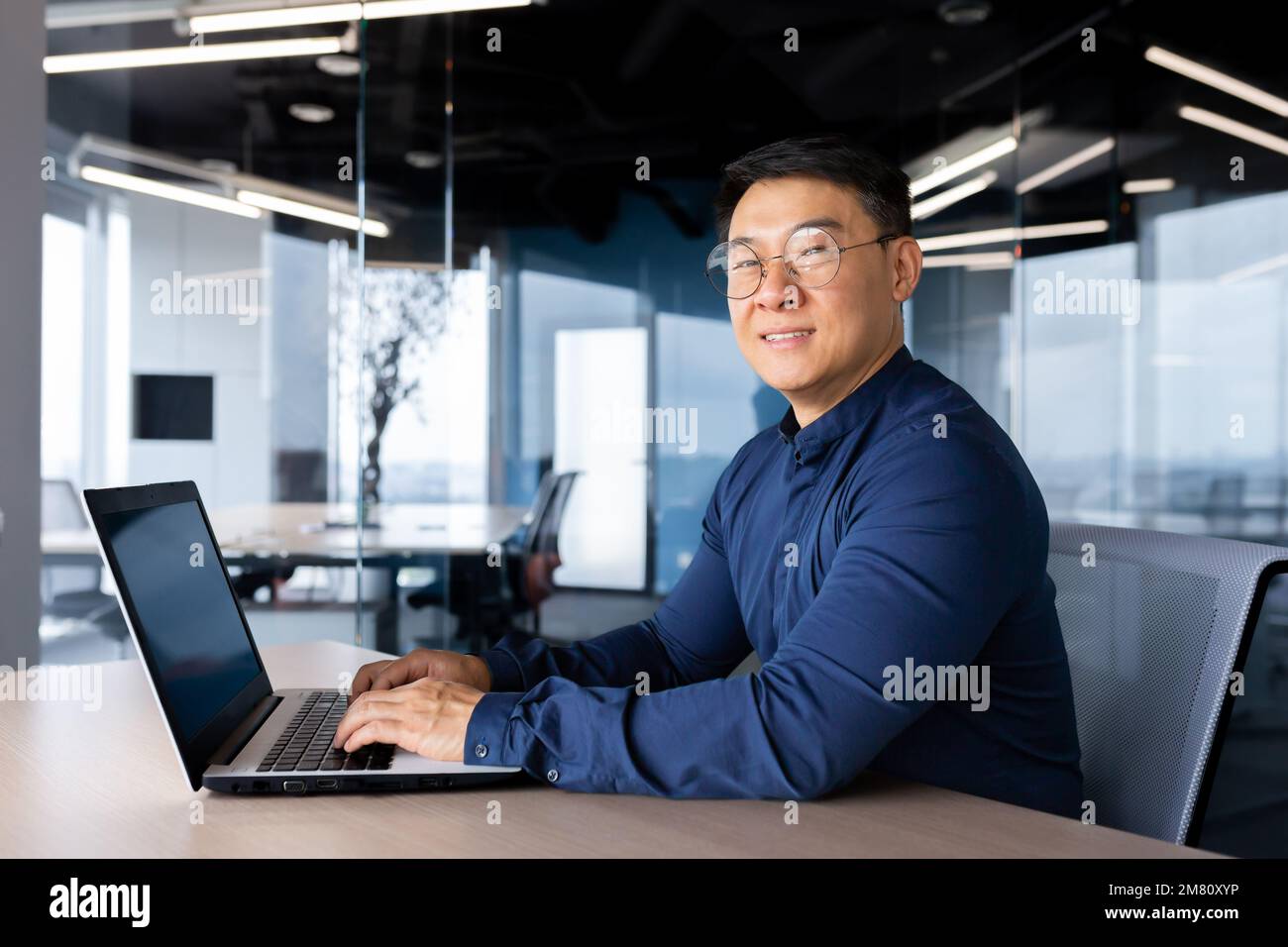 Portrait of a young male Asian student studying at a laptop. Sitting at ...