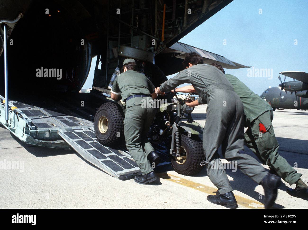 Air Force personnel push a three-wheeled all-terrain vehicle into the ...