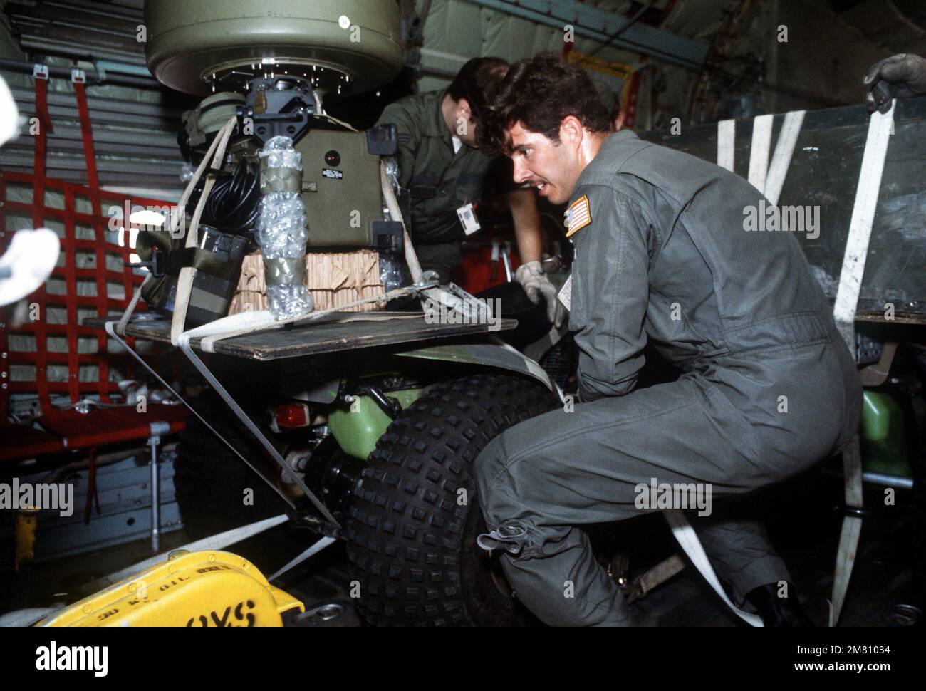 Air Force personnel tie down a three-wheeled all-terrain vehicle in the ...