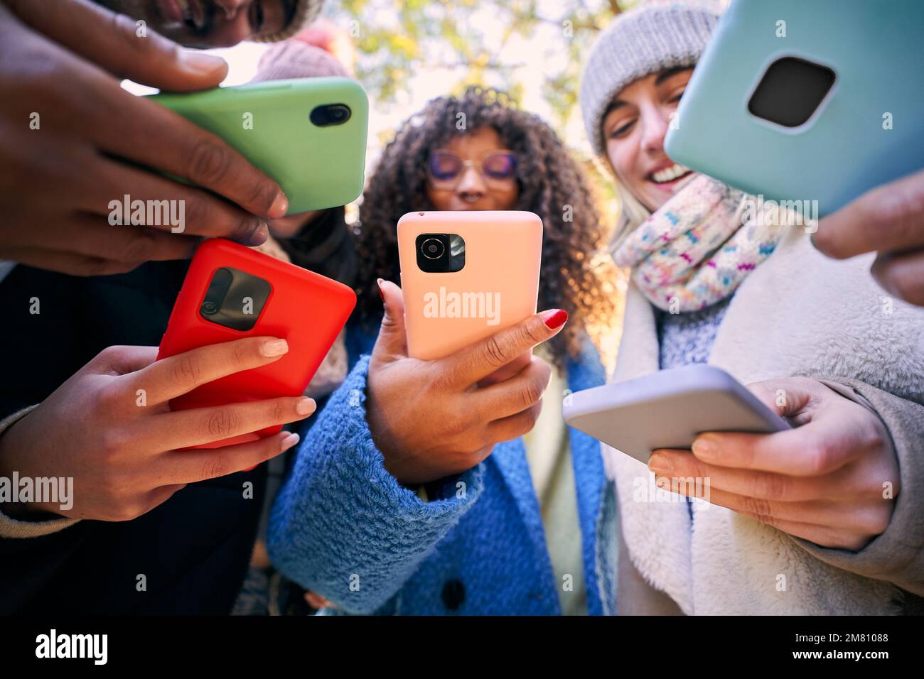 Low angle view of a group of young teenagers using cell phones. Concept ...
