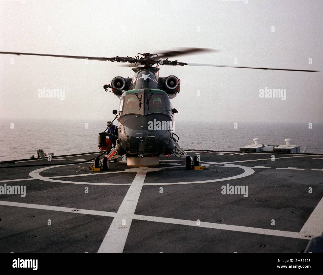 An SH-2 Sea Sprite helicopter is refueled on the helicopter pad of the ...