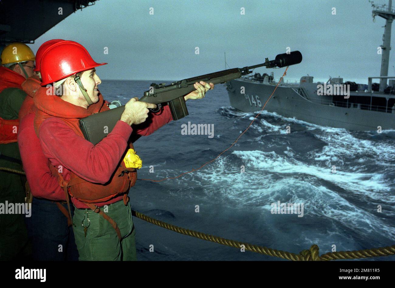 A crewmember aboard the aircraft carrier USS KITTY HAWK (CV 63) fires ...