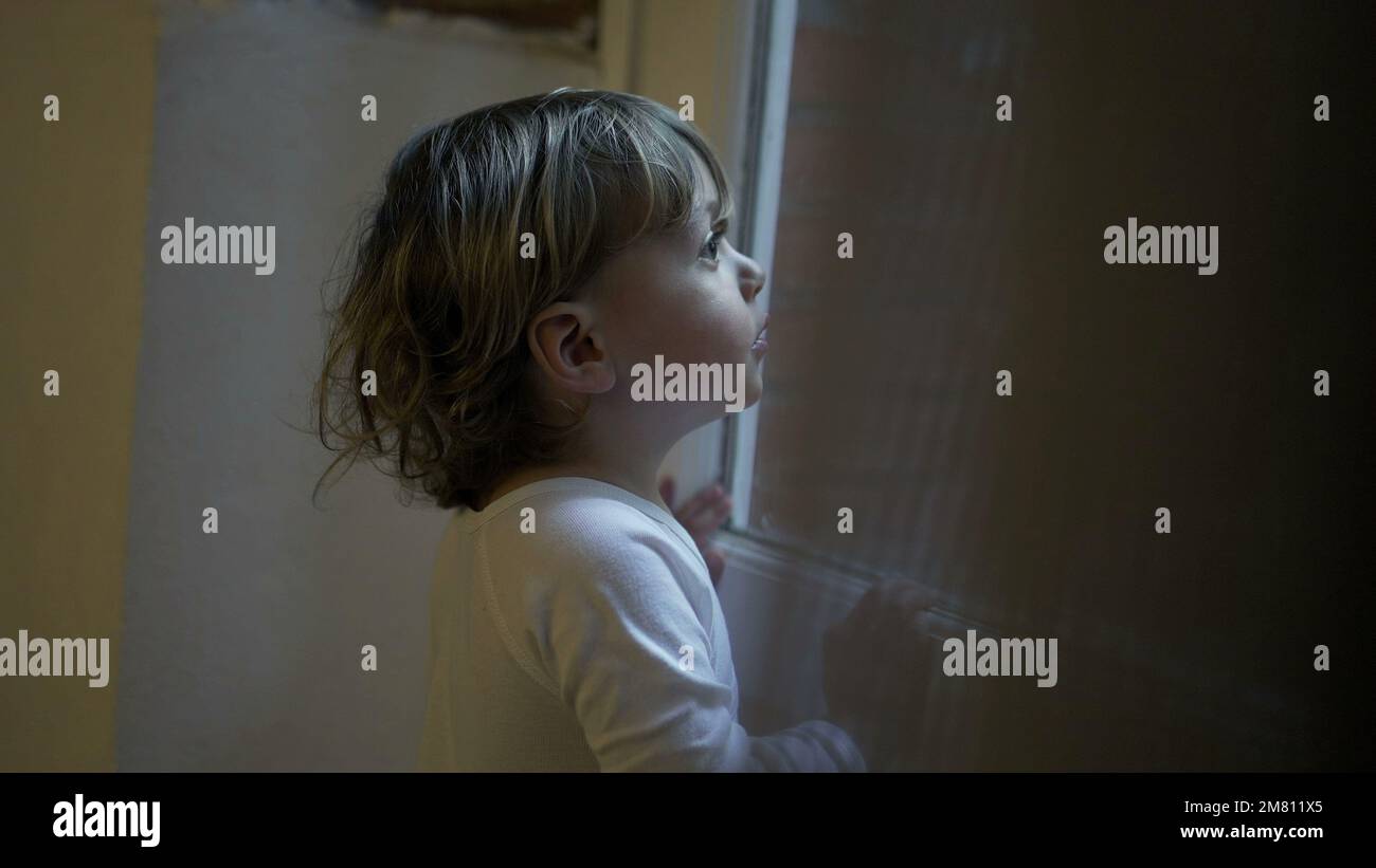 Toddler child staring outside standing by window at home2 Stock Photo ...