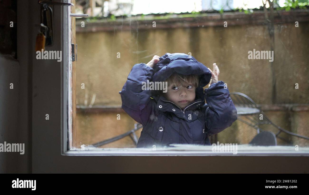 Toddler child leaning on window looking through glass. Baby two year ...