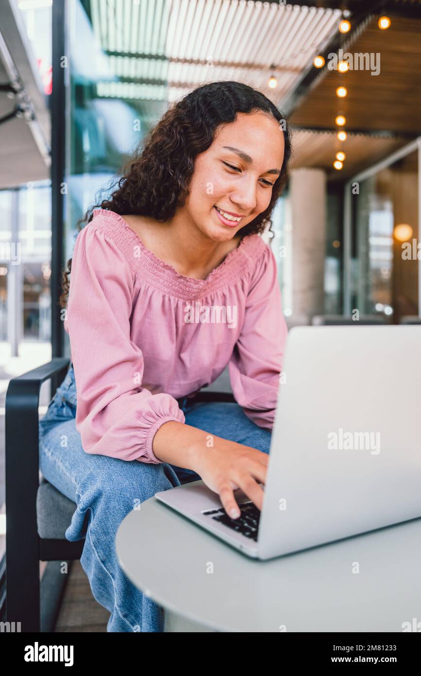 Peaceful young black woman using a computer and sitting outside a cafe ...