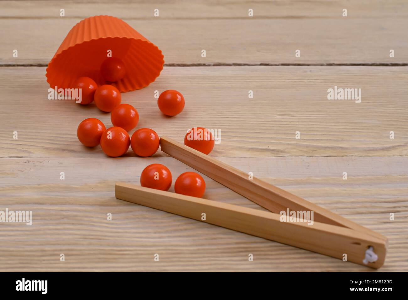a Montessori game. Red balls with wooden tweezers. Develop fine motor ...
