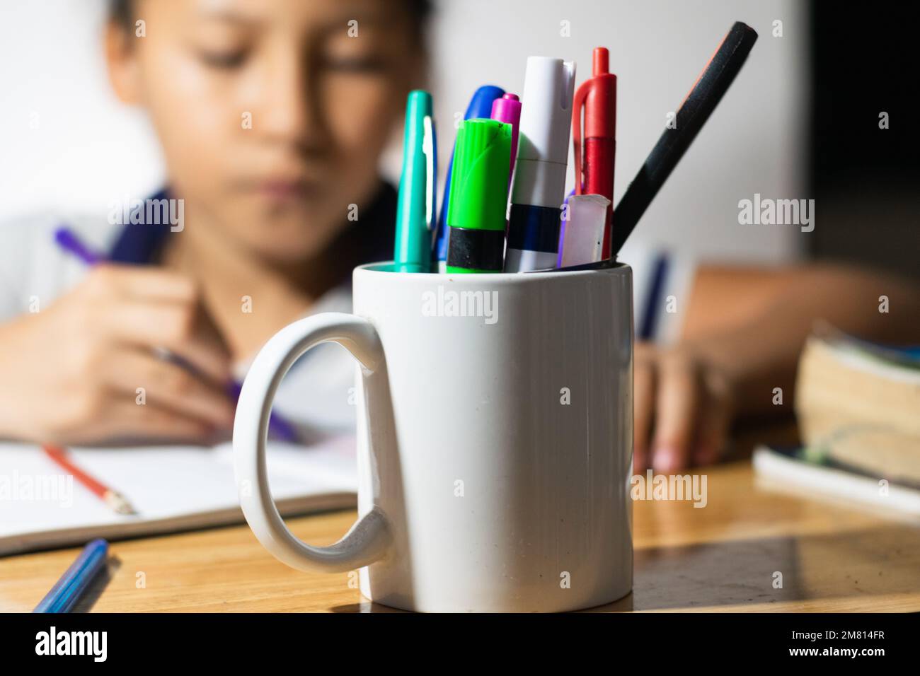 detailed view of a white cup full of pens and school supplies, in the ...