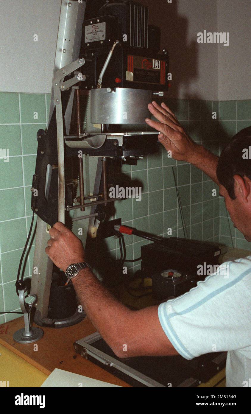 A photographer uses a print enlarger while processing film inside a lab ...