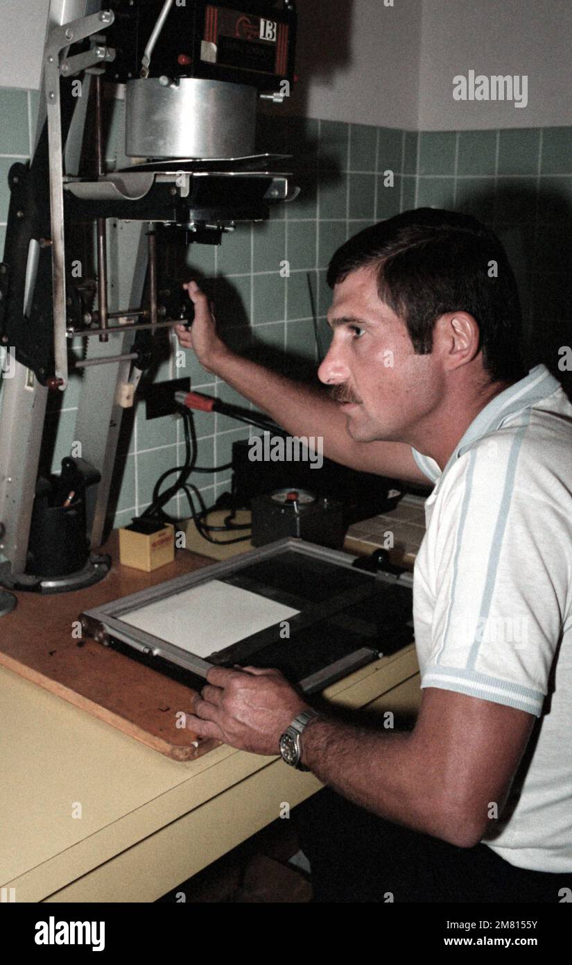 A photographer uses a print enlarger while processing film inside a lab ...