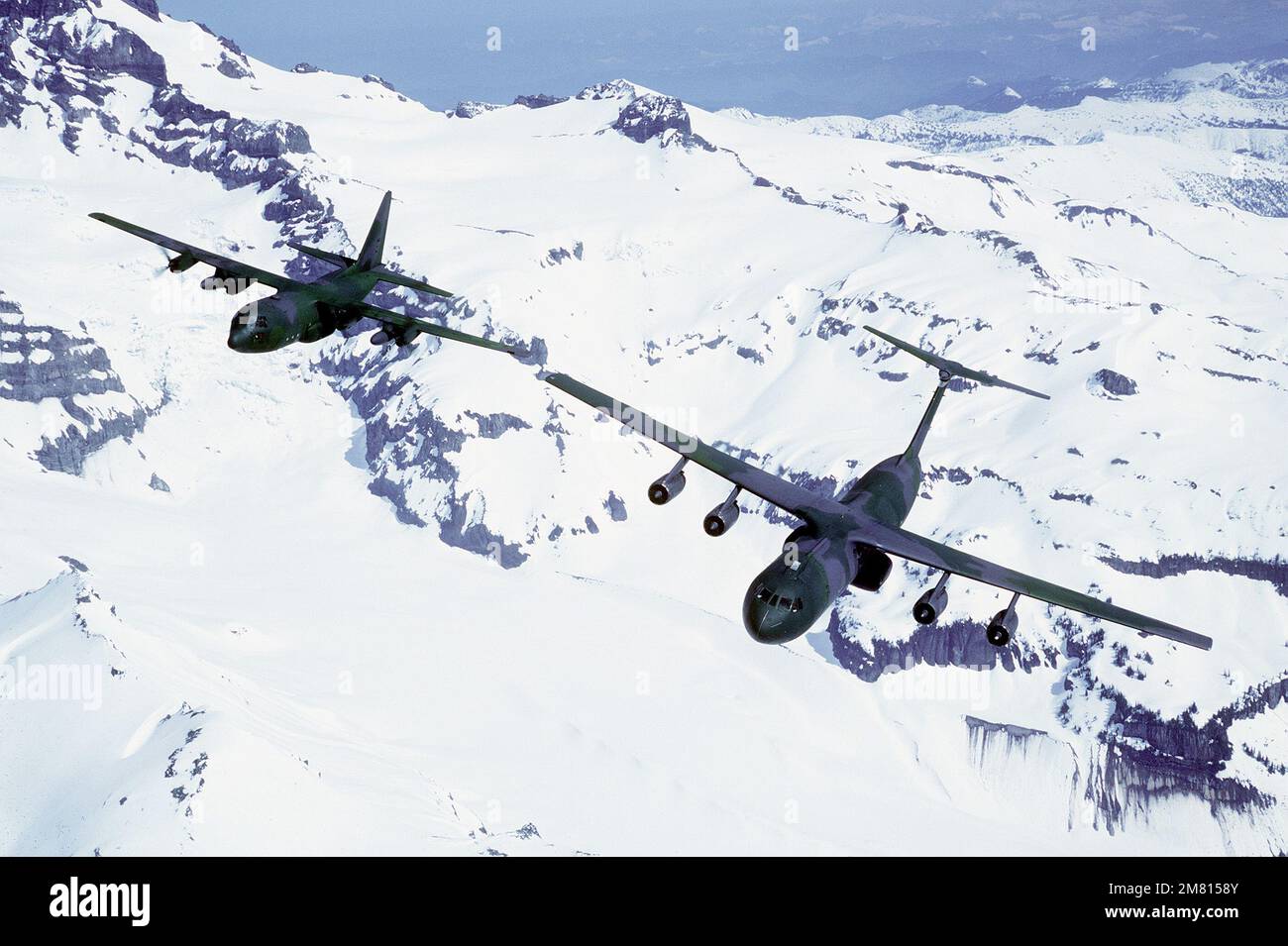 An air-to-air front view of a C-141 Starlifter aircraft (right) from ...