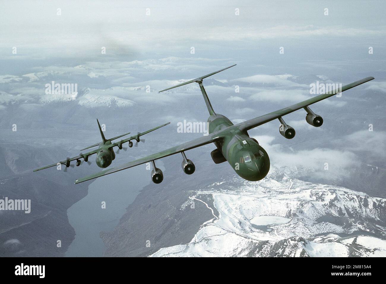 An air-to-air front view of a C-141 Starlifter aircraft (right) from ...