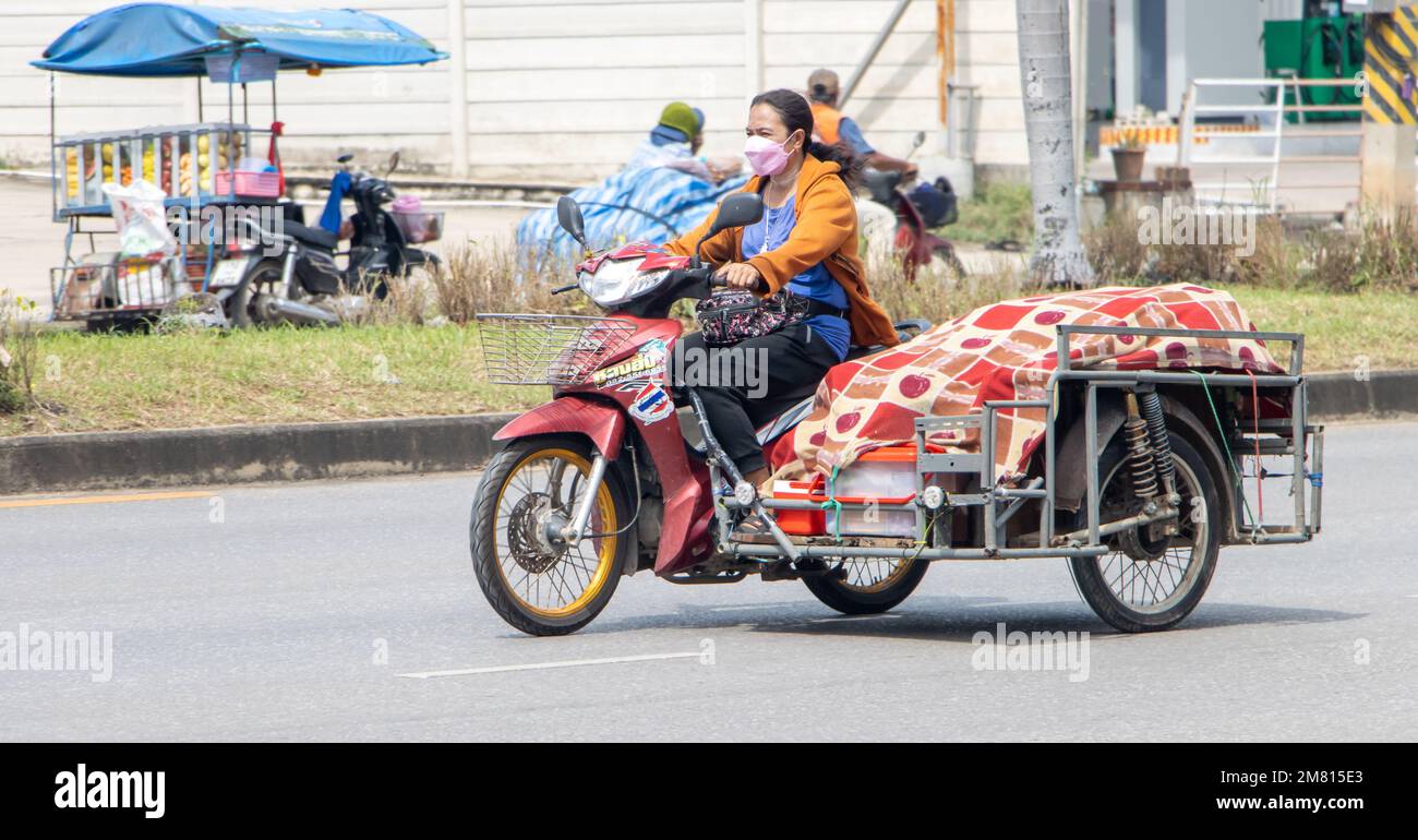 RATCHABURI, THAILAND, NOV 16 2022, A woman drives a motorcycle with an ...