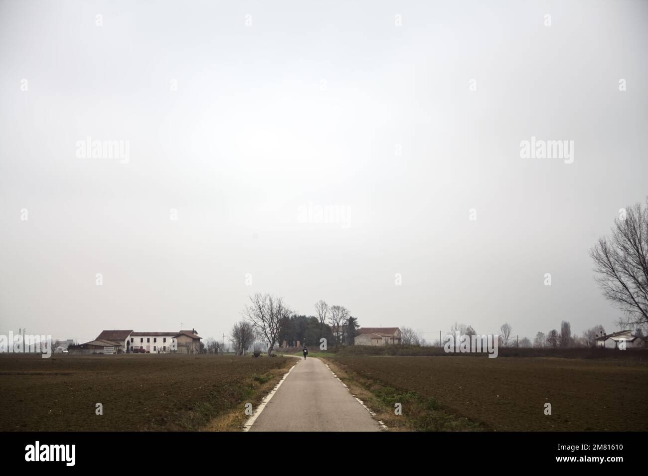 Country house at the end of a narrow road between ploughed fields on a ...
