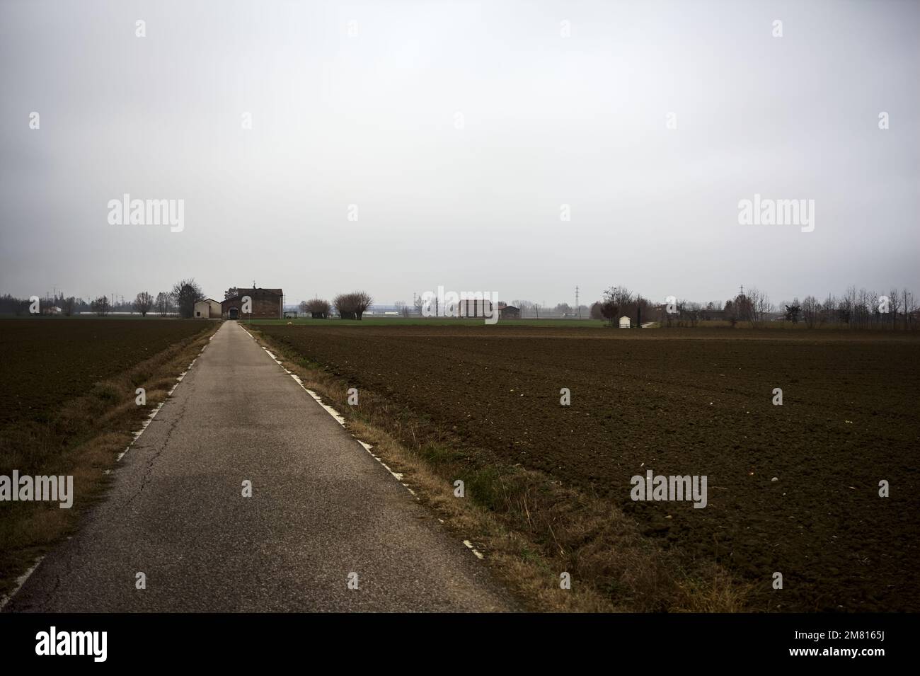 Country house at the end of a narrow road between ploughed fields on a ...