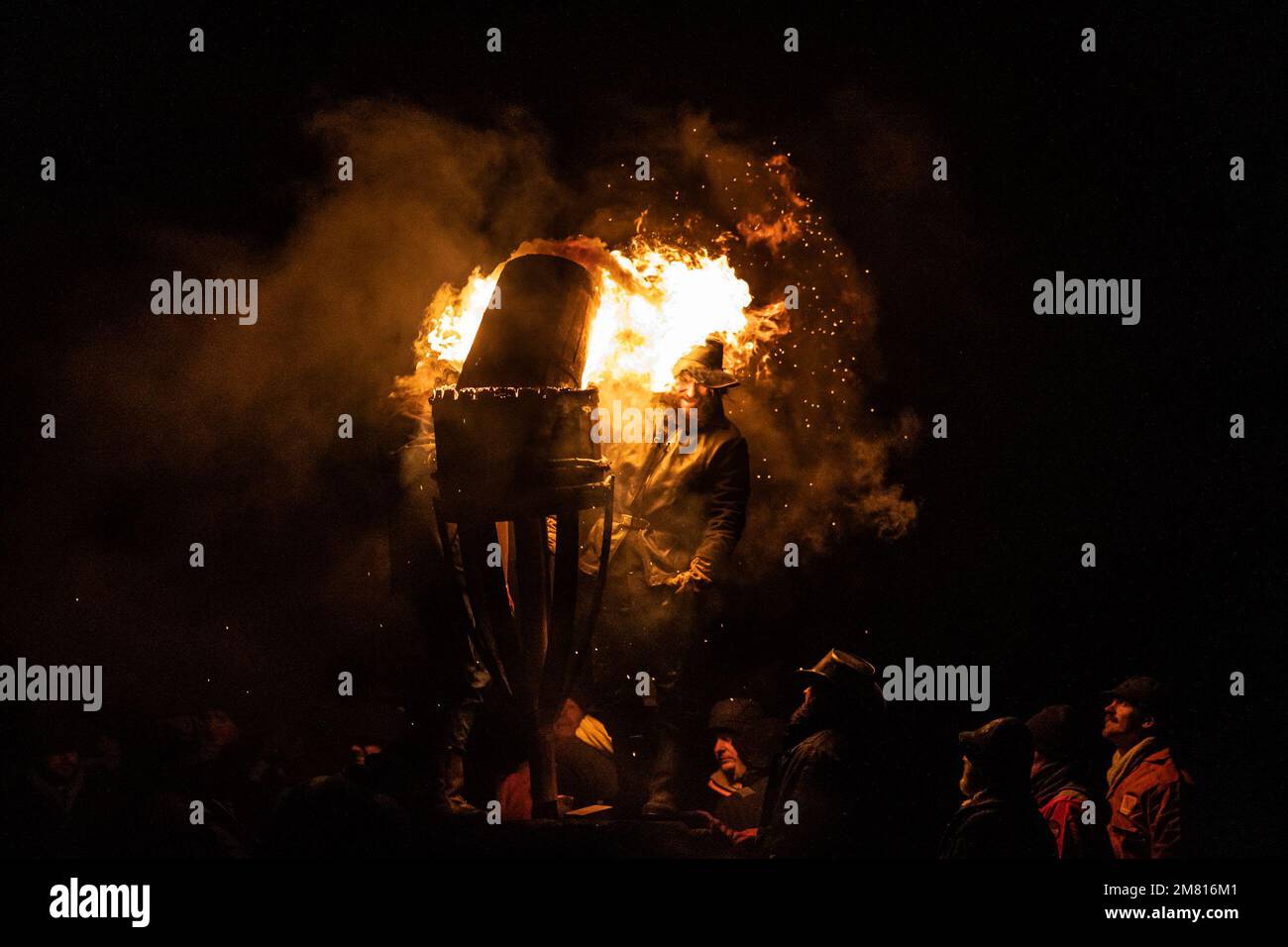 People carry a burning barrel of tar during the Burning of the Clavie ...