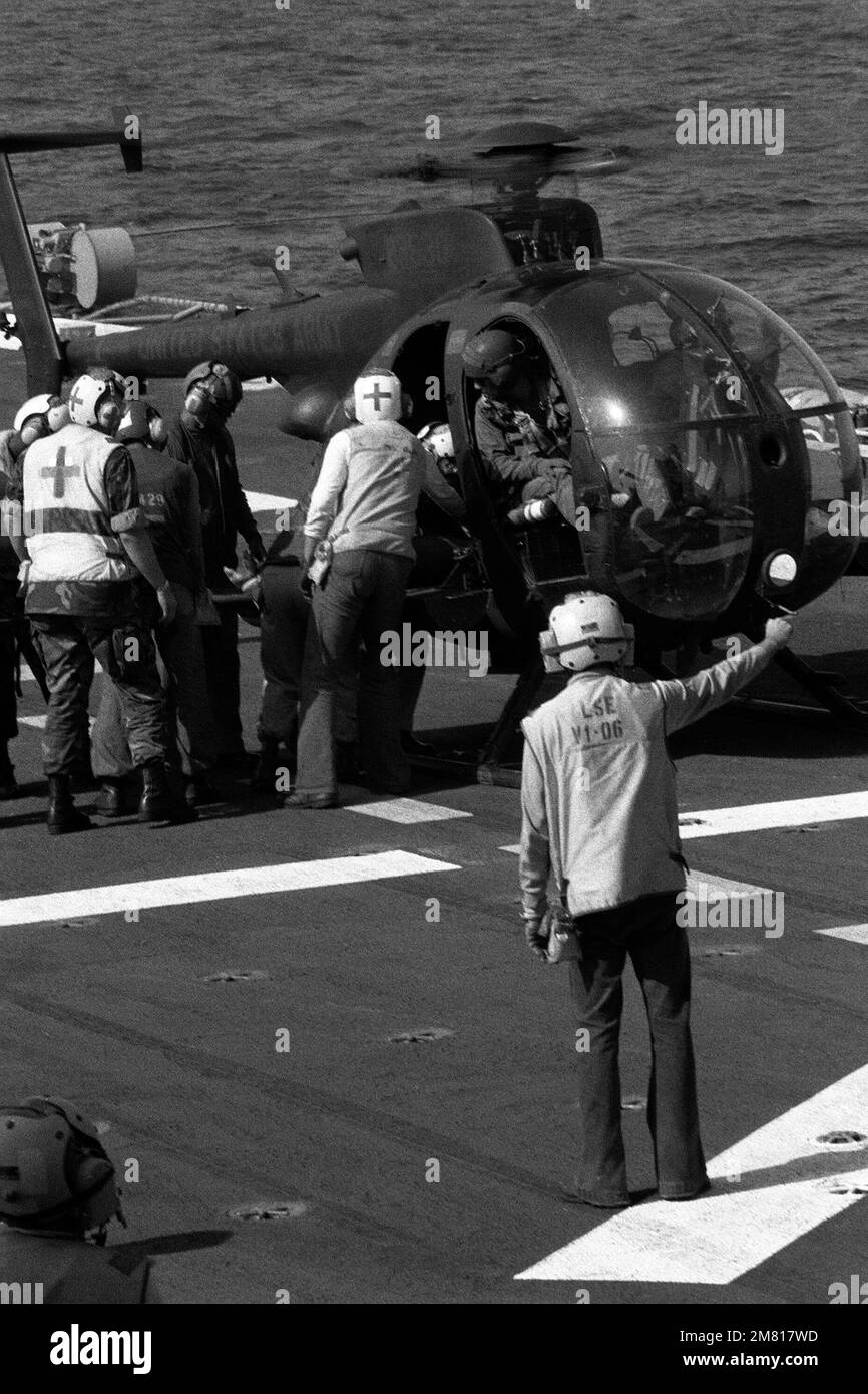 Flight deck crewmen and medical personnel remove a wounded serviceman ...