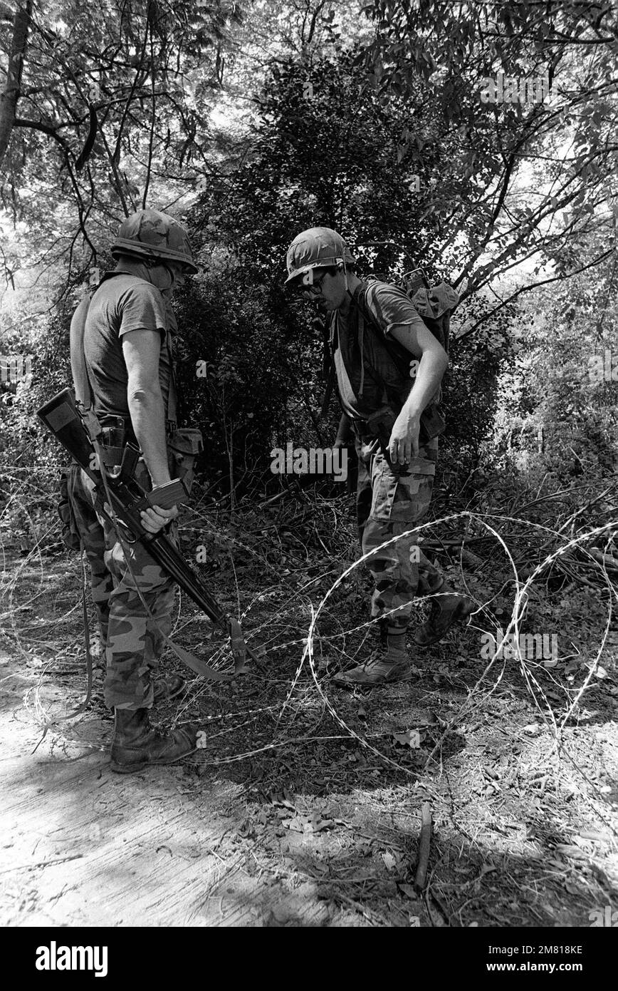 Members of the US Air Force security team examine concertina wire as ...