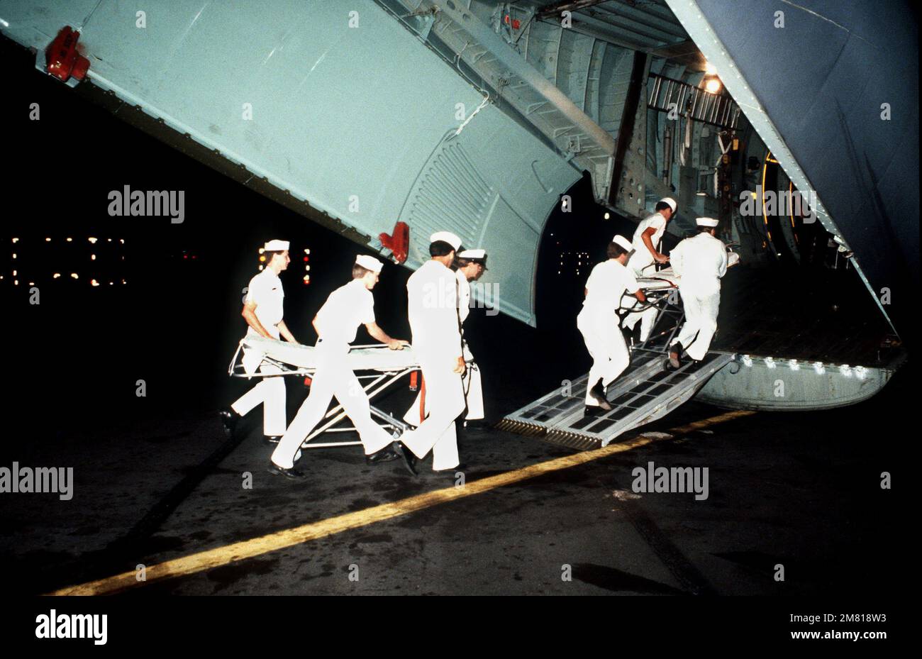 US Navy personnel roll stretchers into a transport aircraft during the ...