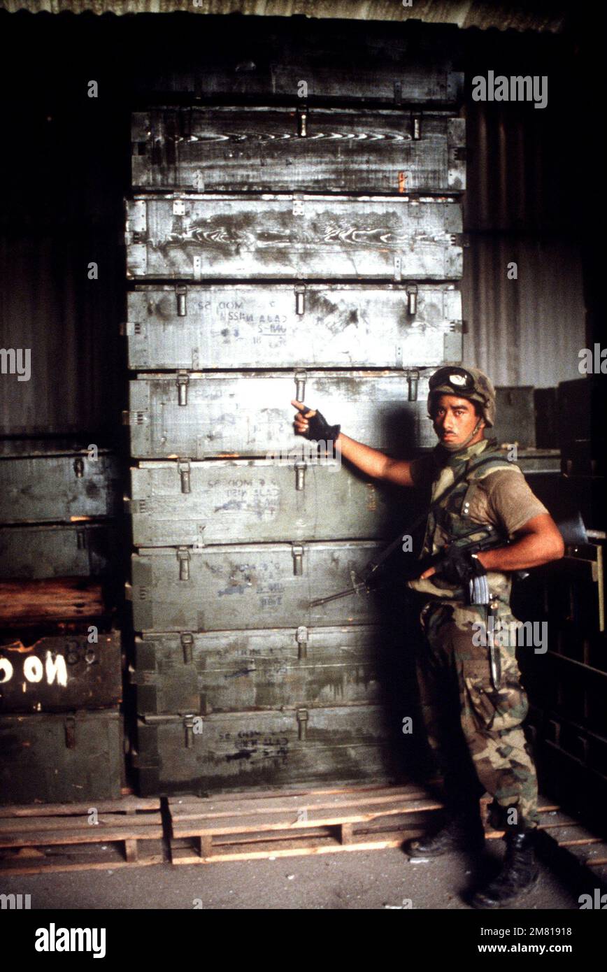 A member of the 82nd Airborne Division points to Cuban supplies captured during Operation URGENT ...