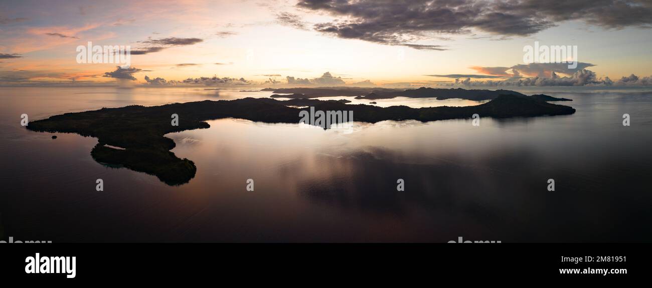 Sunrise illuminates clouds that drift over the calm waters of the ...
