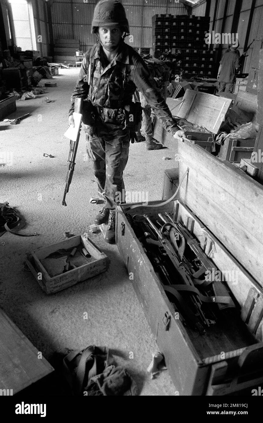 A member of the 82nd Airborne Division examines a crate of AK-47 ...