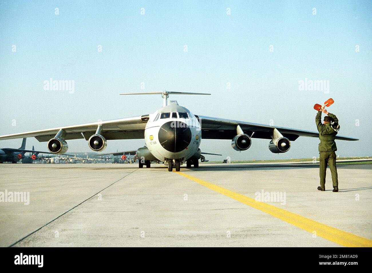 A ground crewman signals the pilot of a C-141 Starlifter aircraft after ...