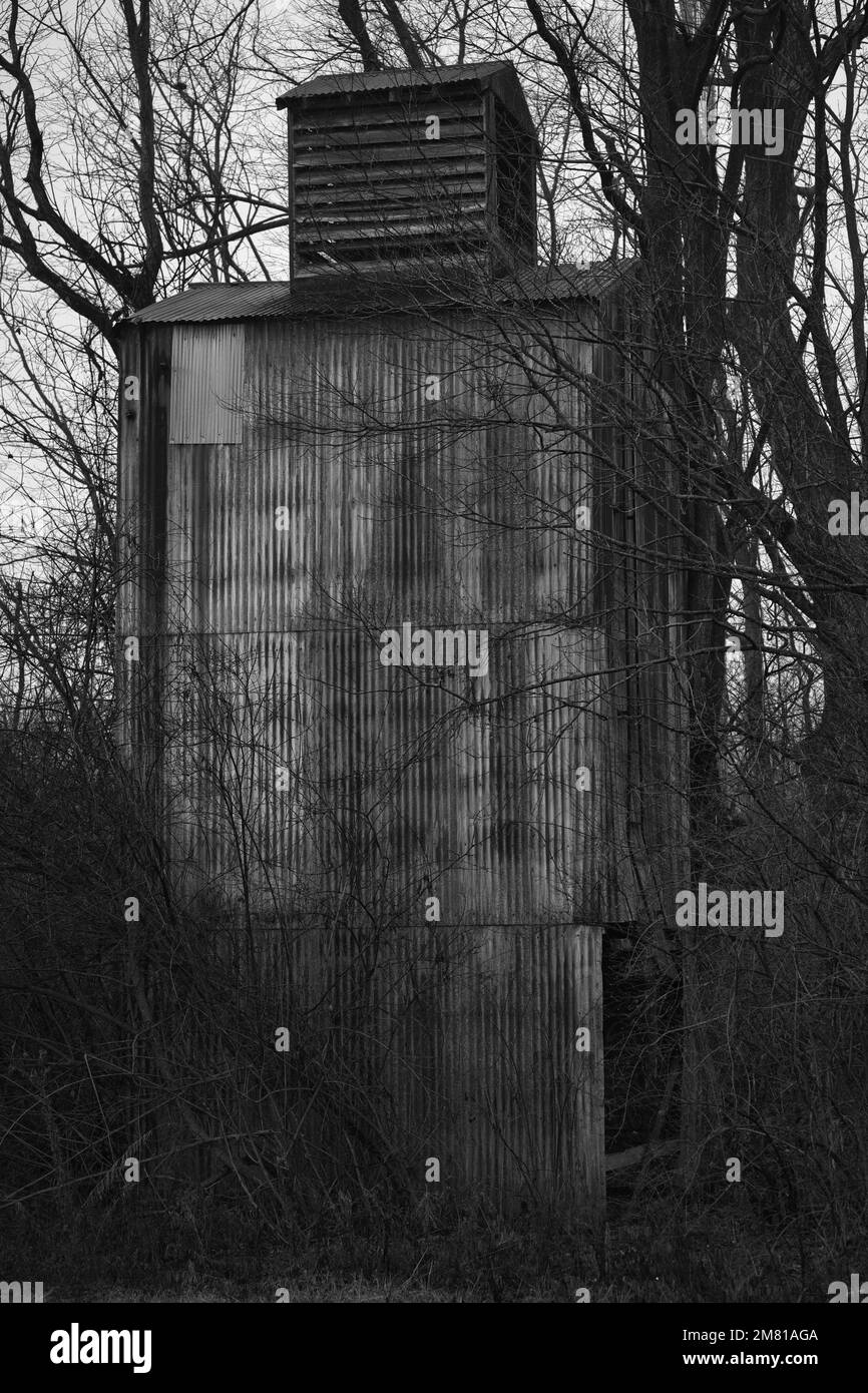 A vertical grayscale of a small old abandoned metal construction in the ...