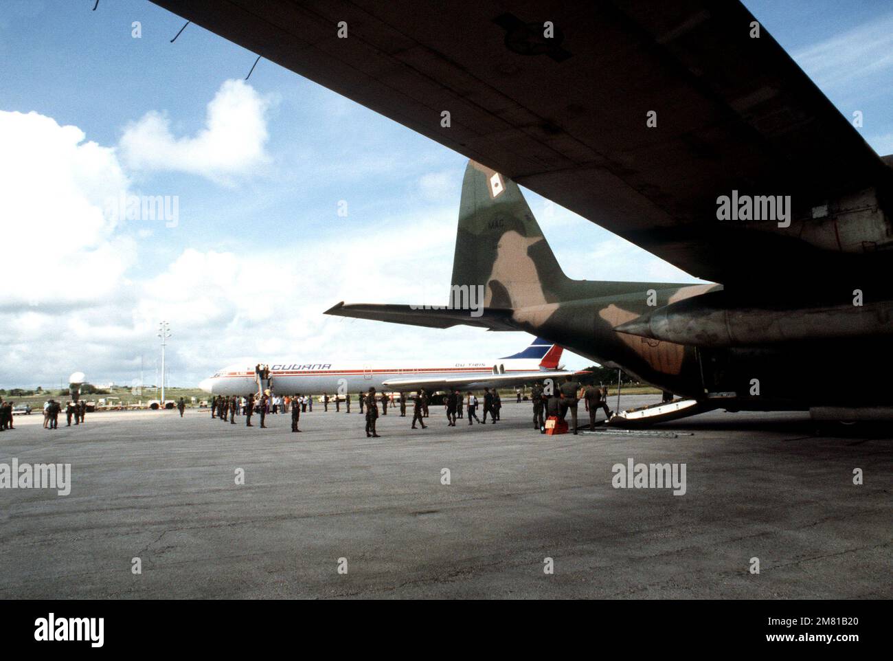 A Cuban I1-62M aircraft is framed by the tail and wing of a C-130 ...