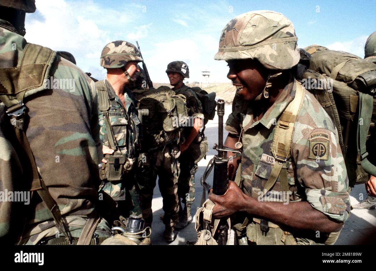 Members of the 82nd Airborne Division wait to board an aircraft at Point Salines Airport during ...
