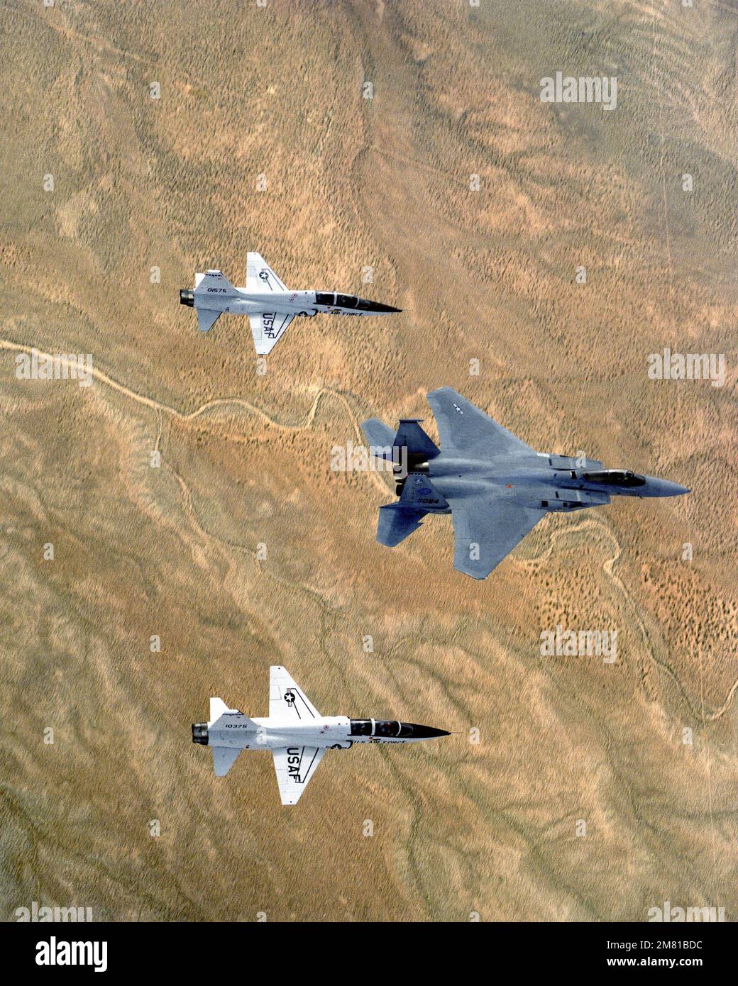 An air-to-air overhead view of an lF-15 Eagle aircraft leading two T-38 ...