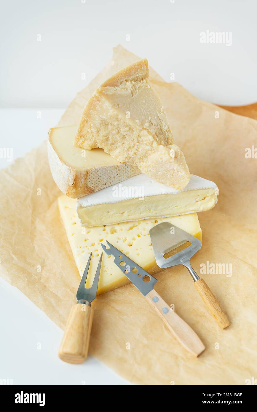 Different types of cheese lie on top of each other with cheese knives ...
