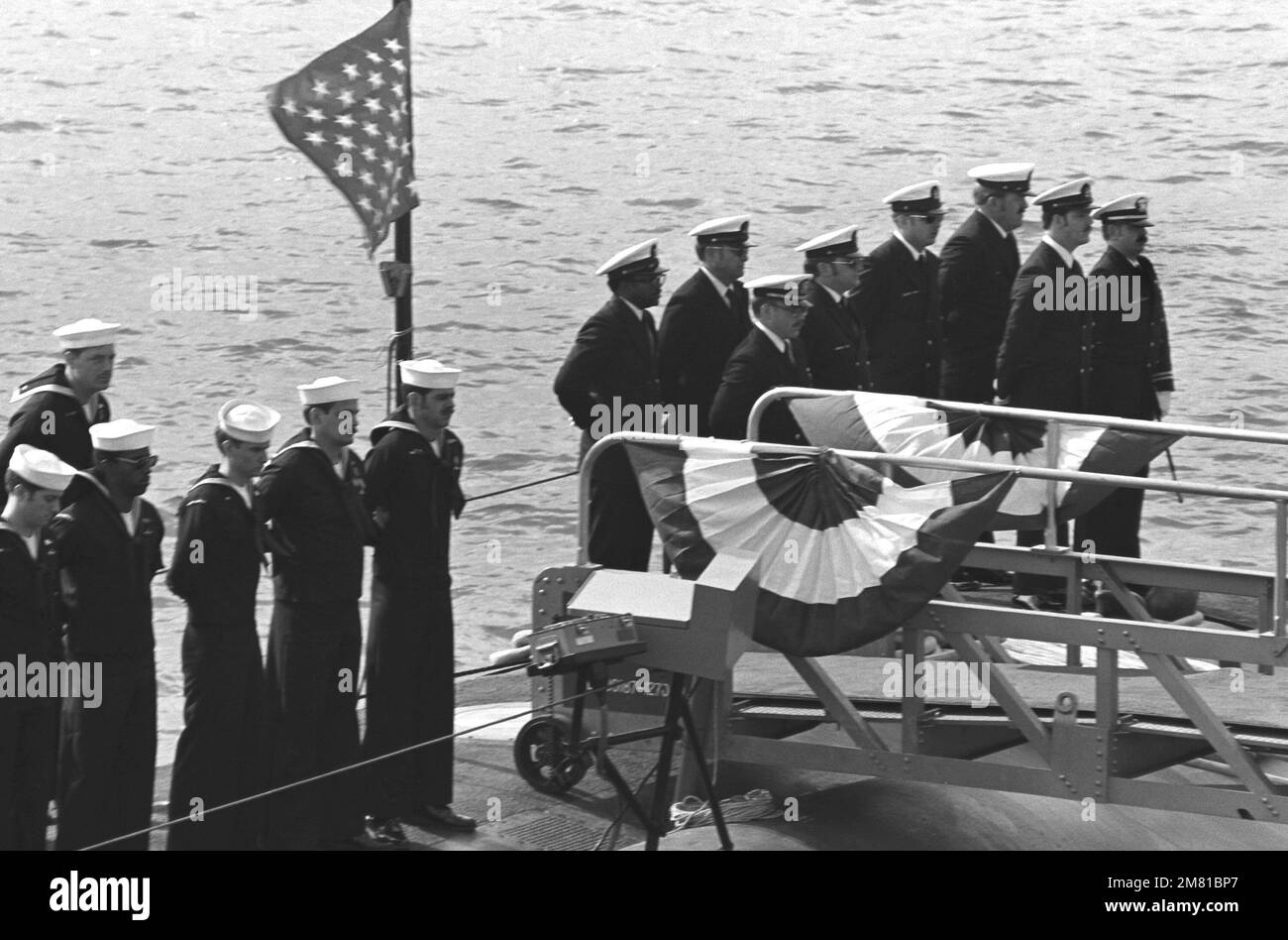 Crew members stand in formation on the deck of the nuclear-powered ...