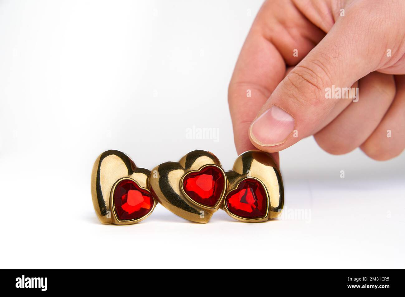 Hand picking golden heart shaped earring with ruby. Closing open ...