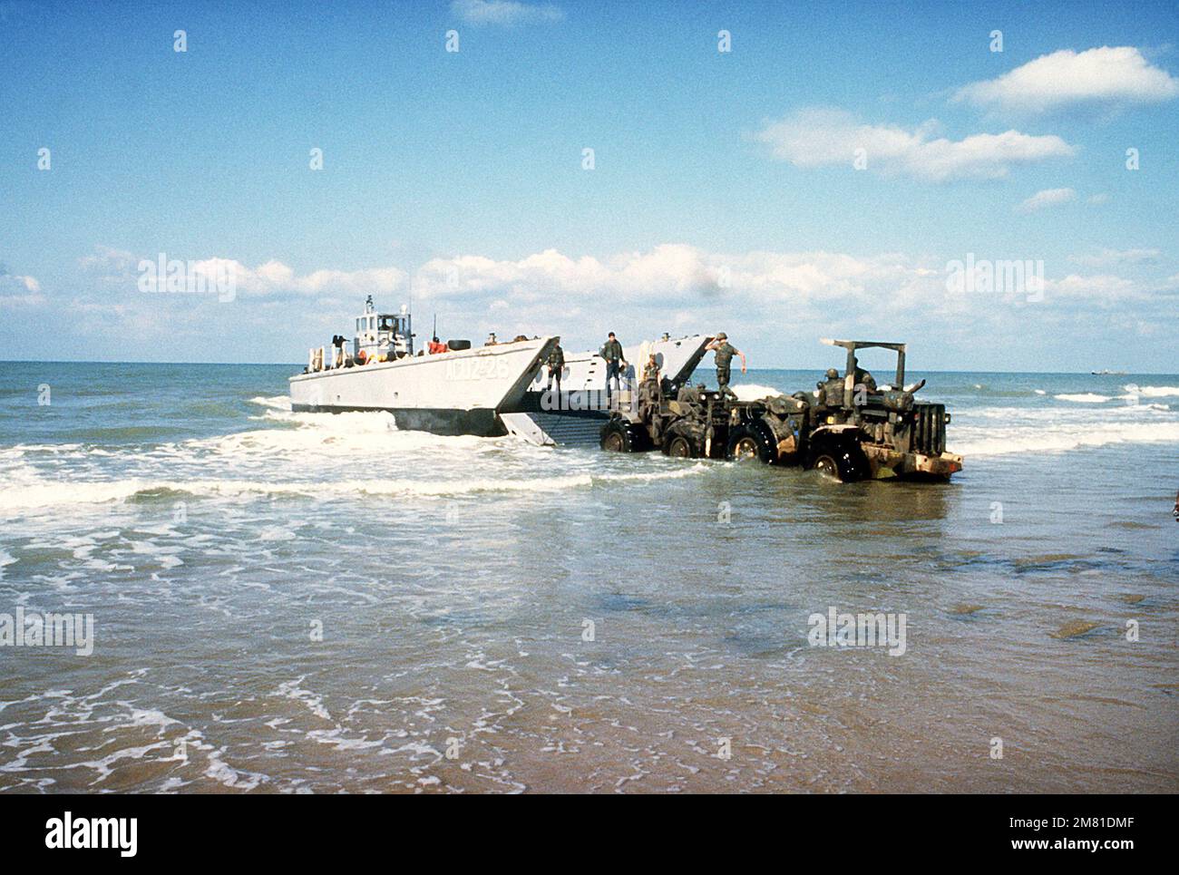 Marine beachmasters load utility vehicles aboard a utility landing ...