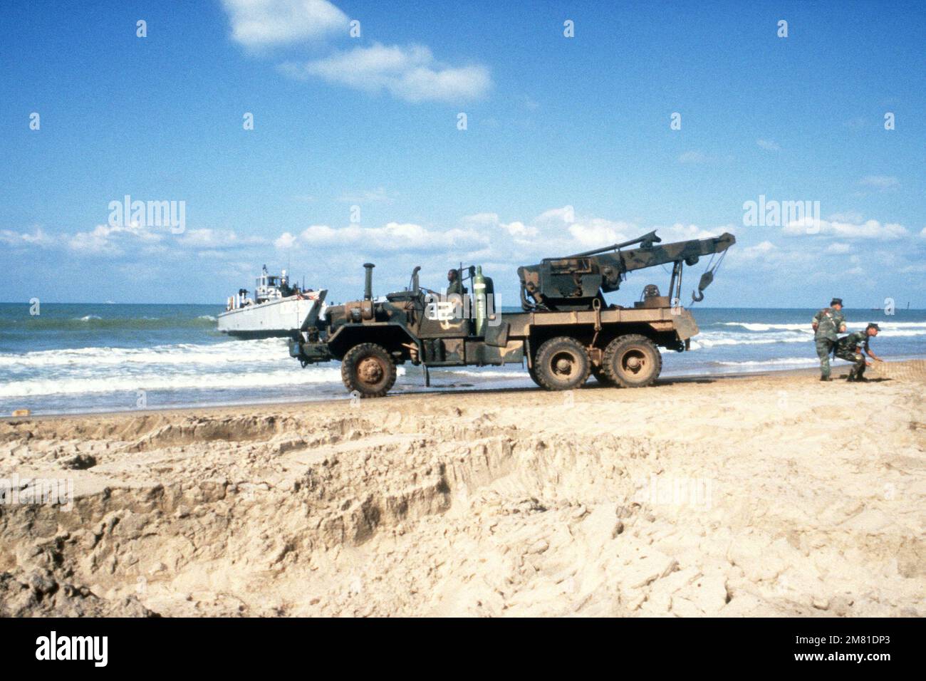 Marine beachmasters prepare to load a truck-mounted crane onto a ...
