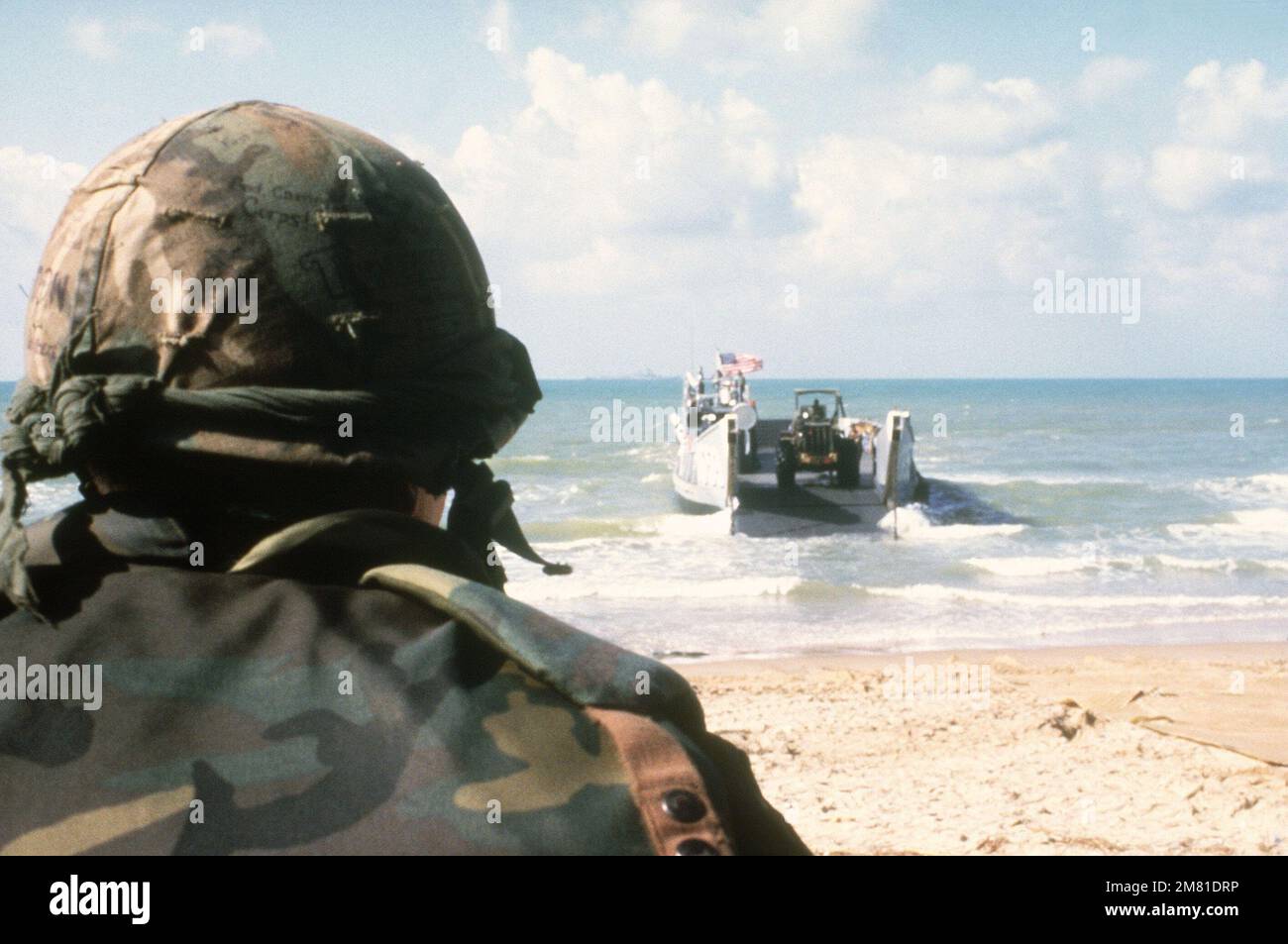 A Marine watches as a utility landing craft is loaded with equipment ...