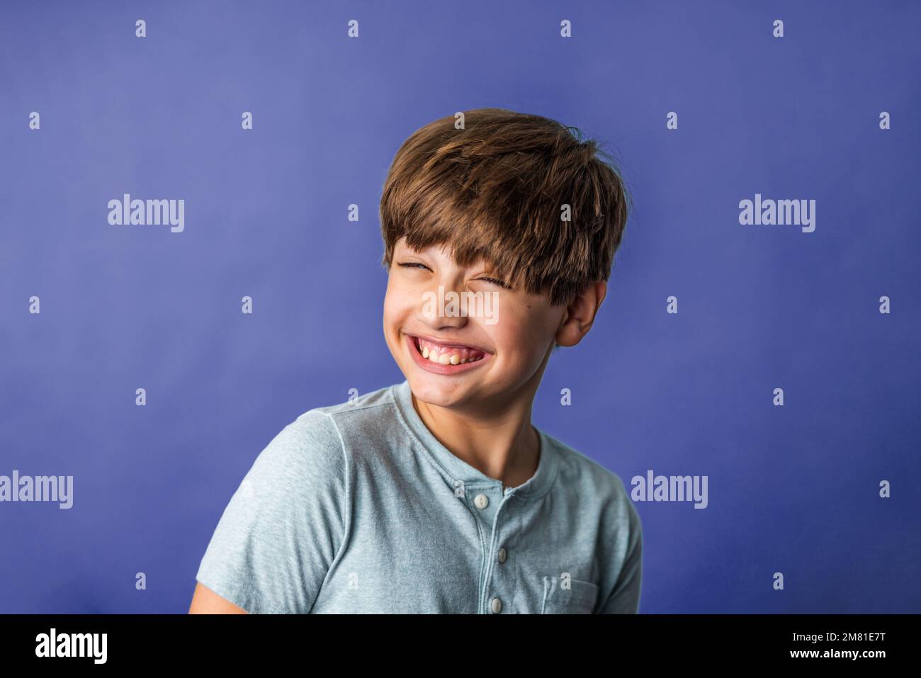 A cute pre-teen tween boy from the shoulders up on a blue purple ...